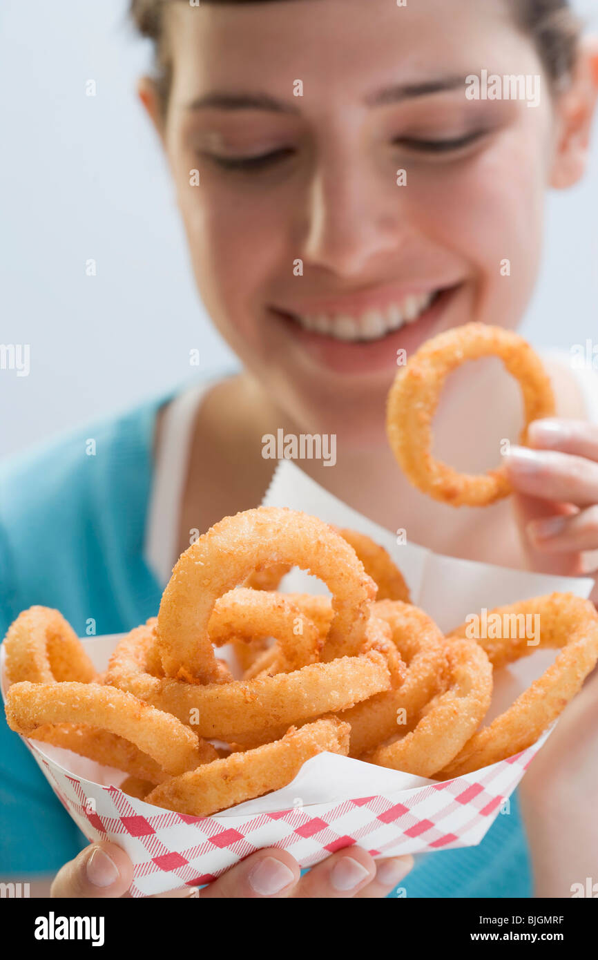 Young woman holding deep-fried onion rings in paper dish Stock Photo ...