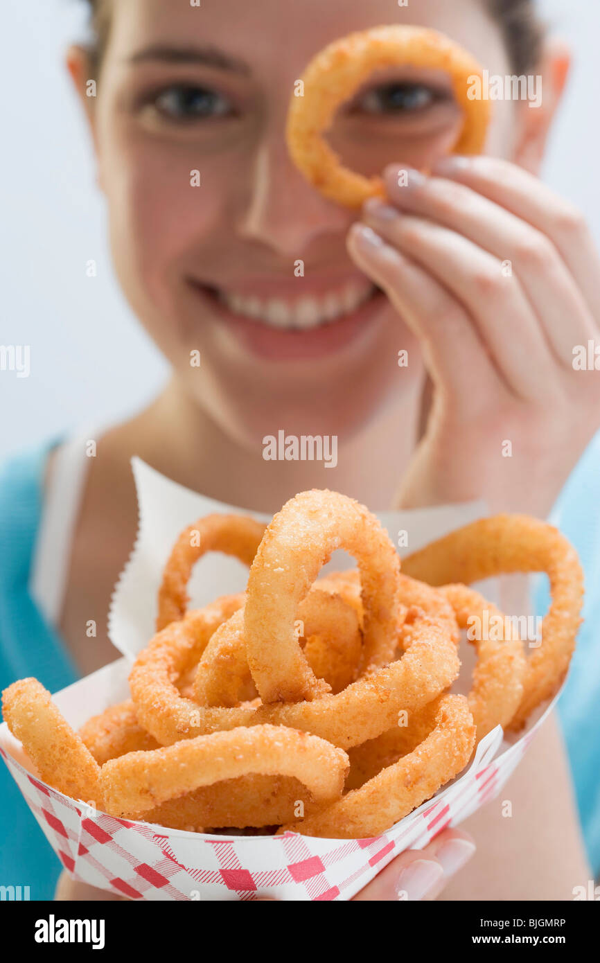 Young woman holding deep-fried onion rings in paper dish Stock Photo ...