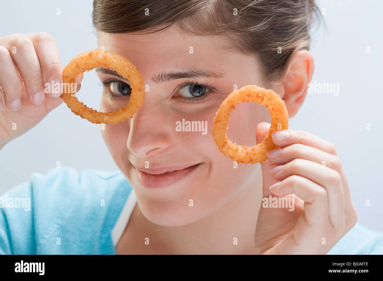 Young woman holding up two deep-fried onion rings Stock Photo - Alamy
