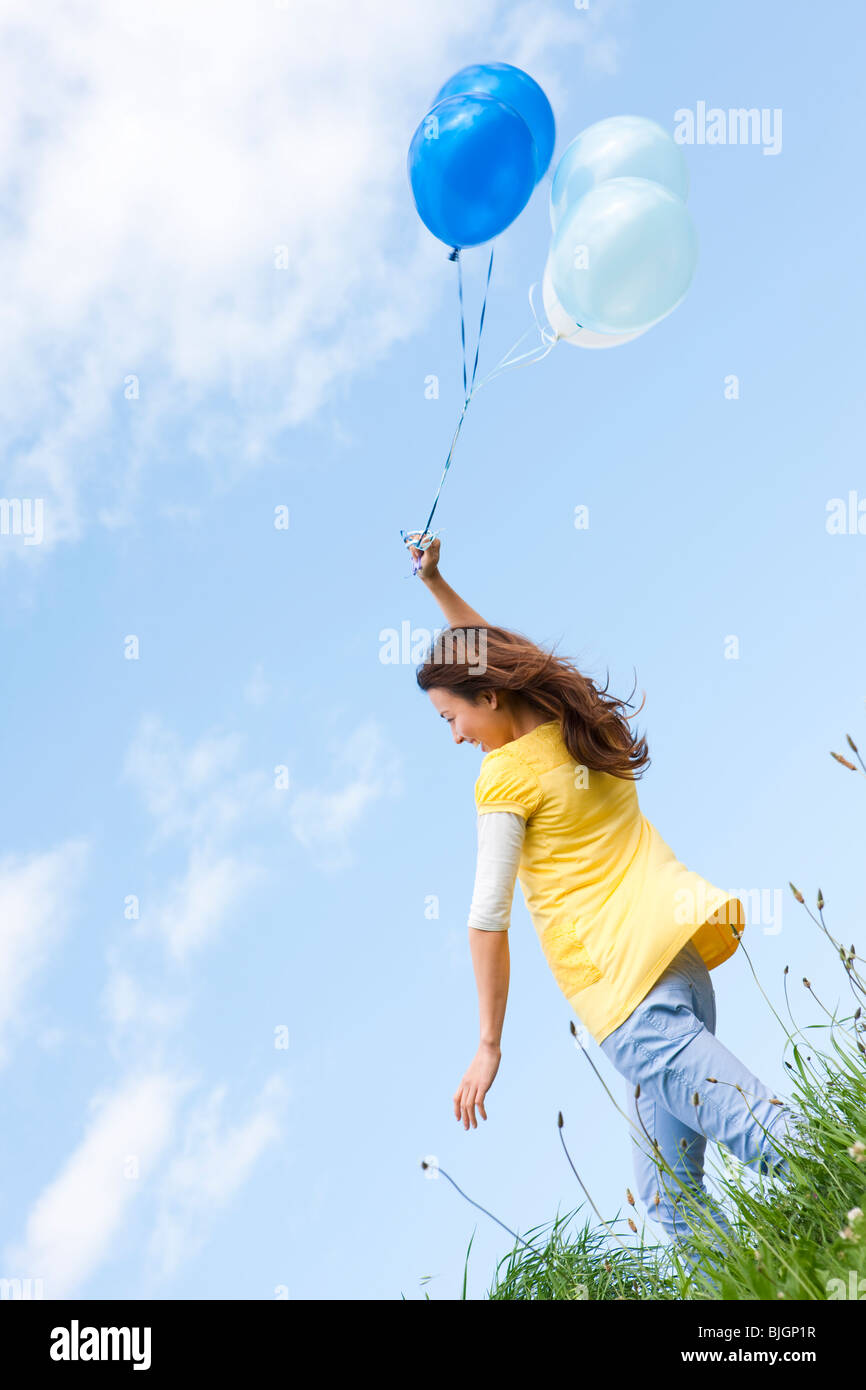 Woman running with balloons Stock Photo - Alamy