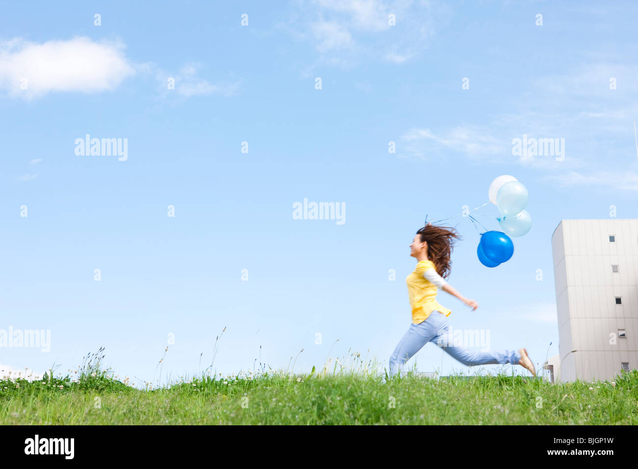 Woman running with balloons Stock Photo - Alamy
