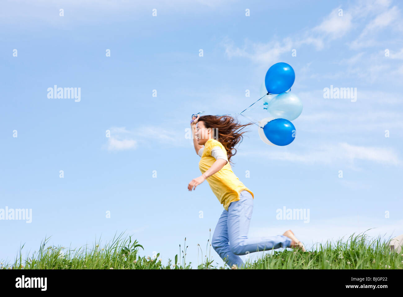 Woman running with balloons Stock Photo - Alamy