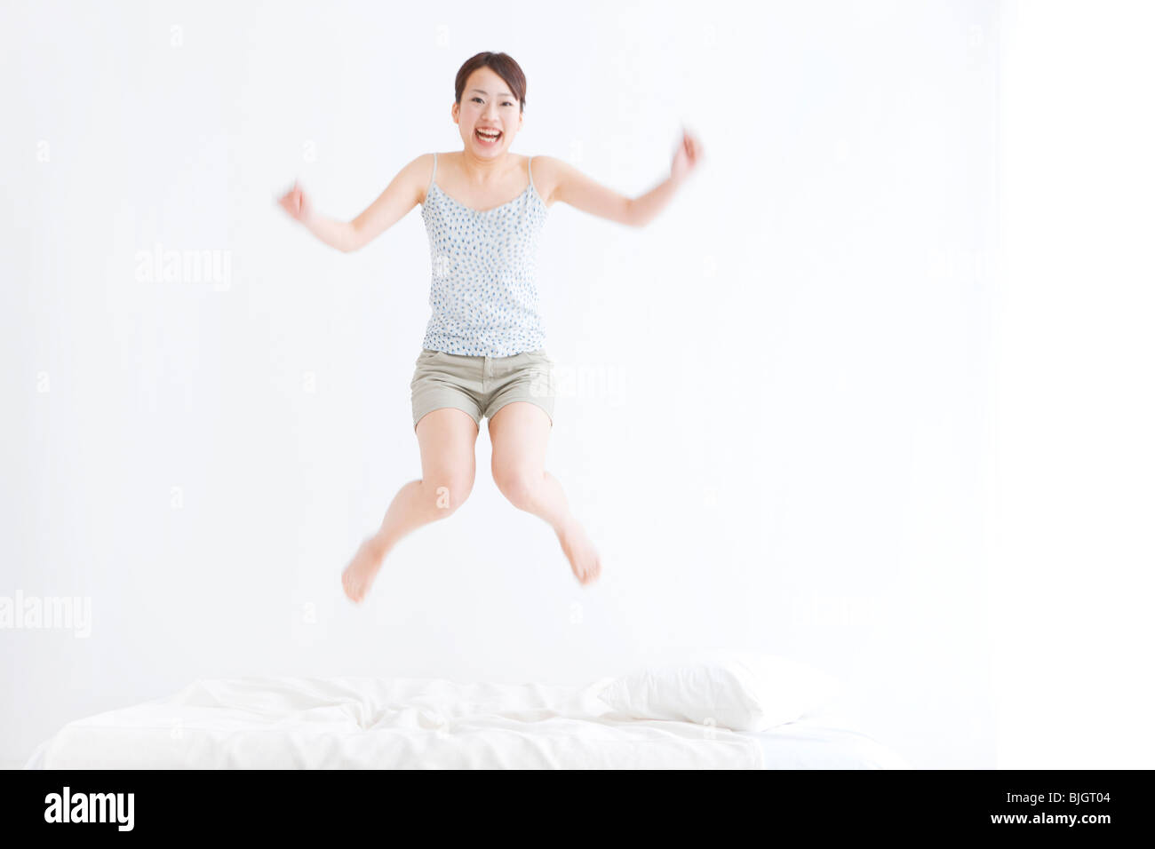 Woman jumping on bed Stock Photo - Alamy