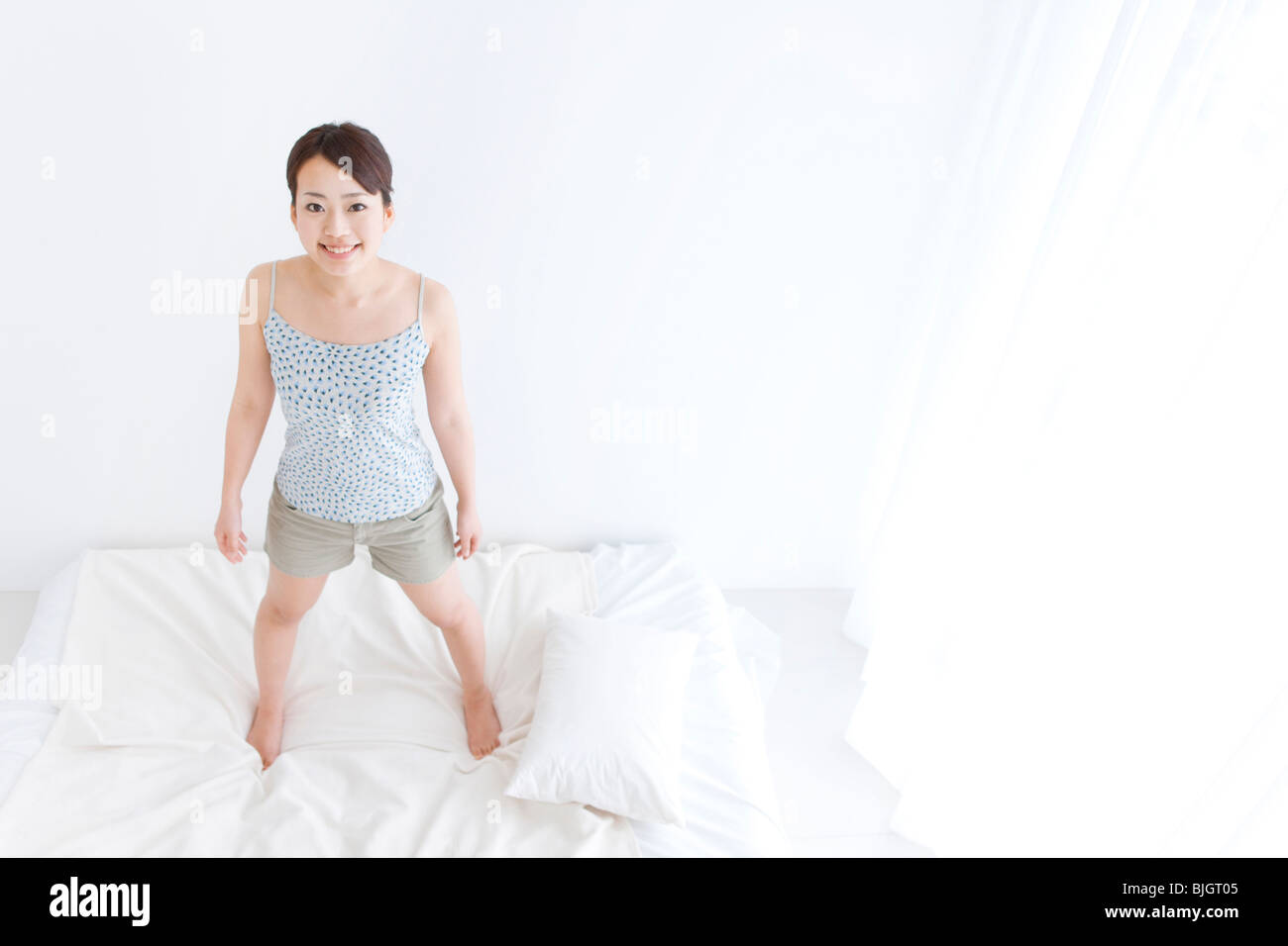 Woman standing on bed Stock Photo - Alamy
