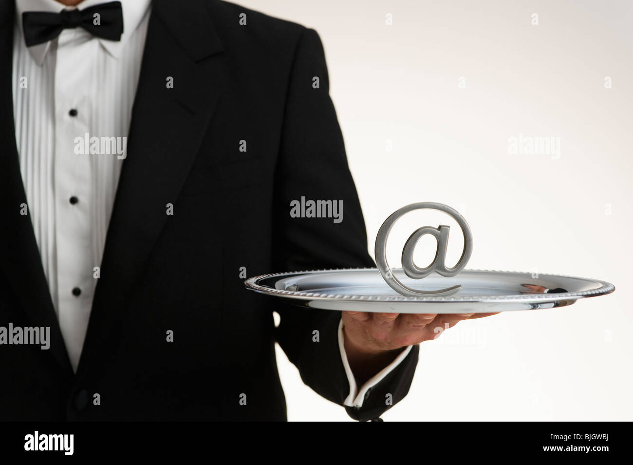 Butler holding at symbol on silver tray Stock Photo - Alamy