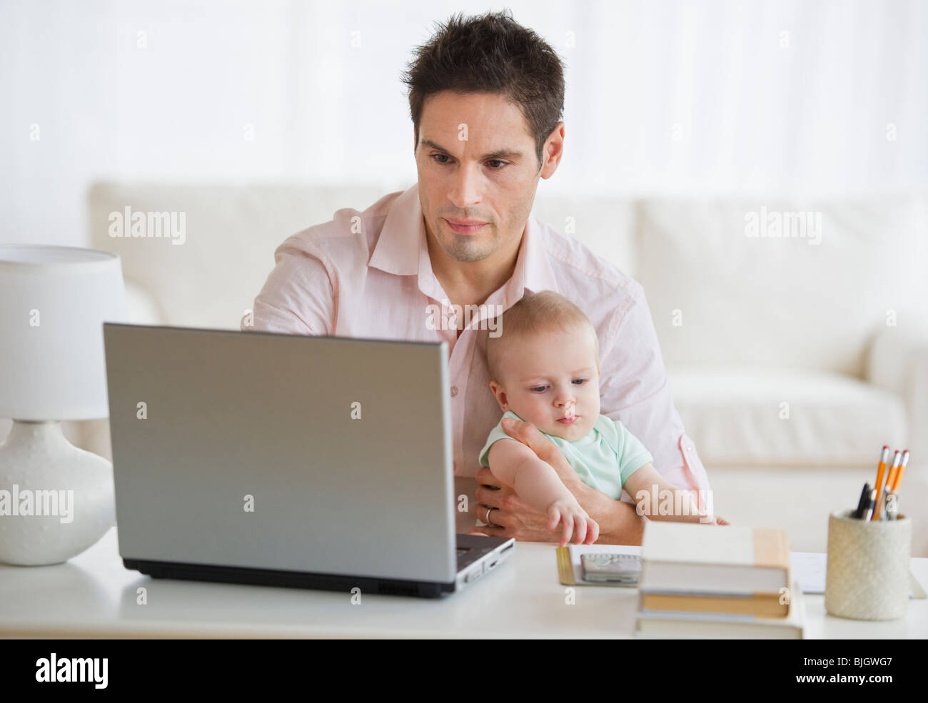 Man holding baby while working Stock Photo - Alamy