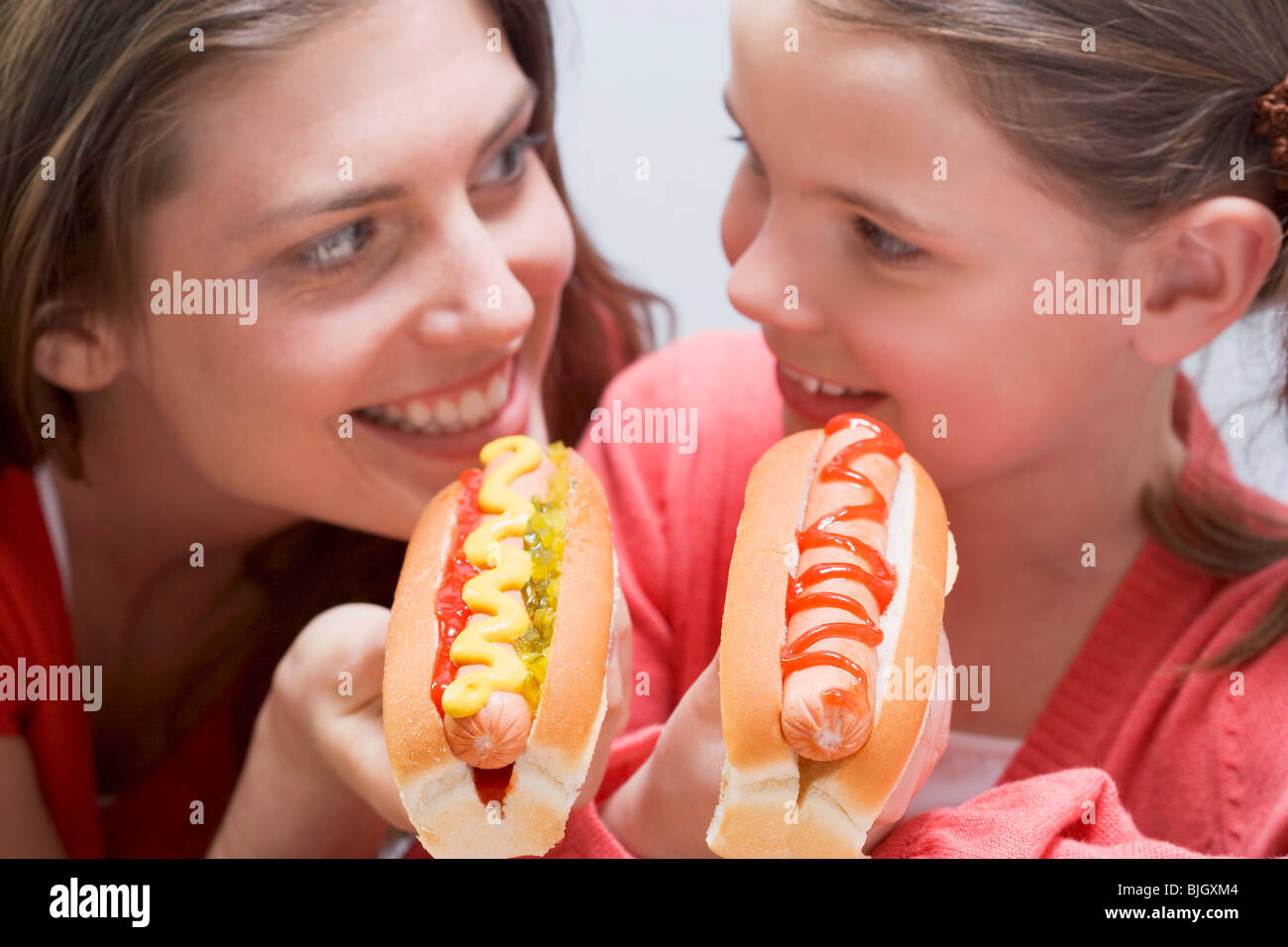 Woman and girl laughing and eating hot dogs Stock Photo - Alamy