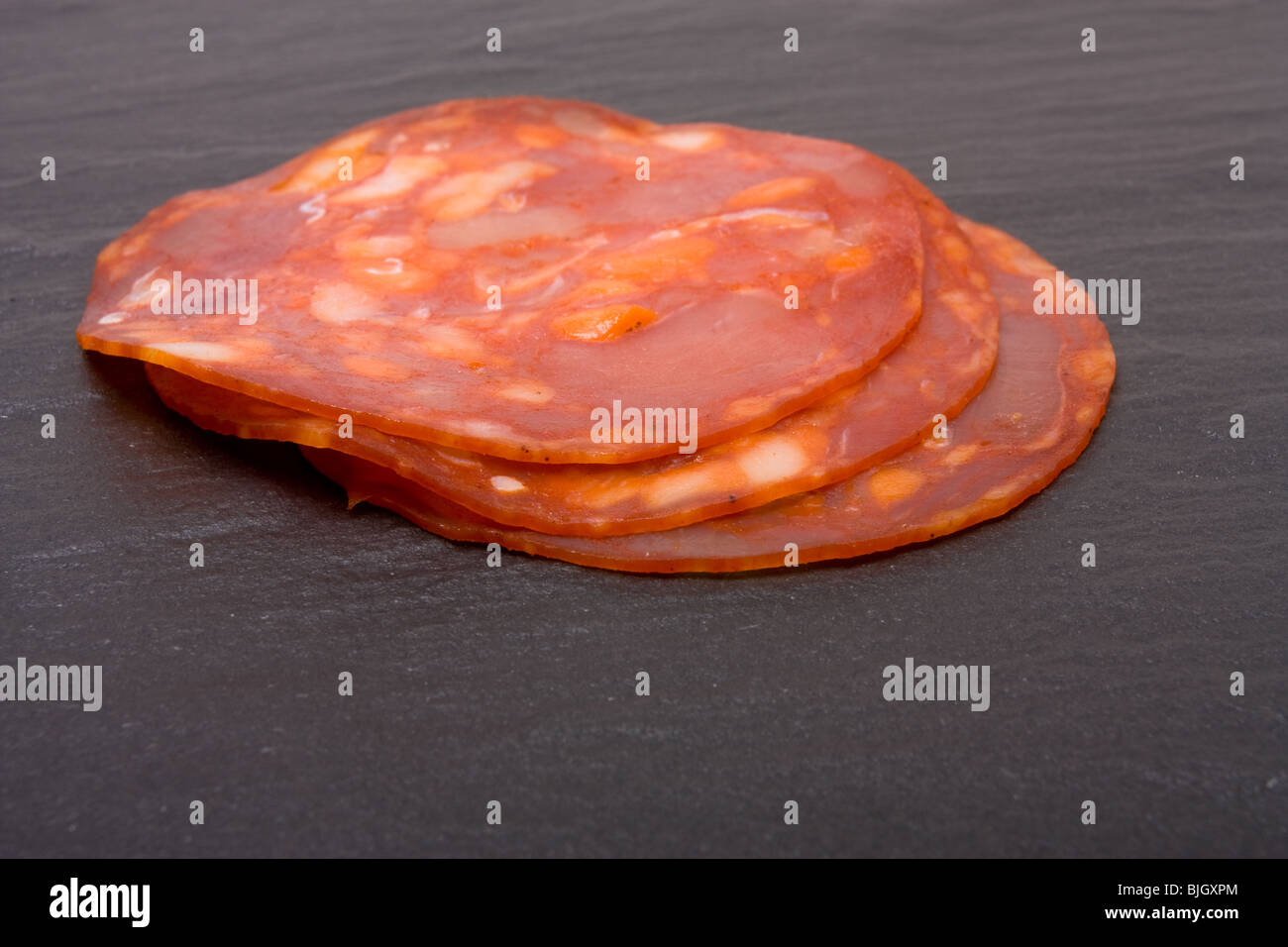 Chorizo Slices from low angle on dark slate background Stock Photo - Alamy