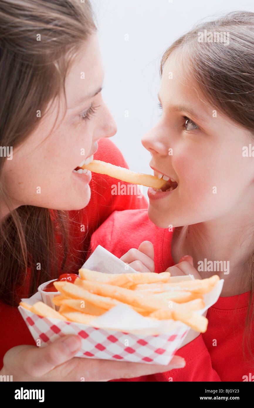 Young woman and girl eating the same chip Stock Photo - Alamy