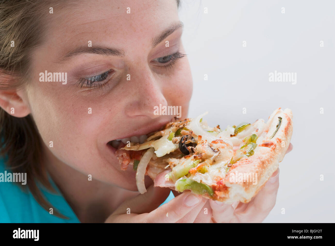 Young woman biting into a slice of vegetable pizza Stock Photo - Alamy