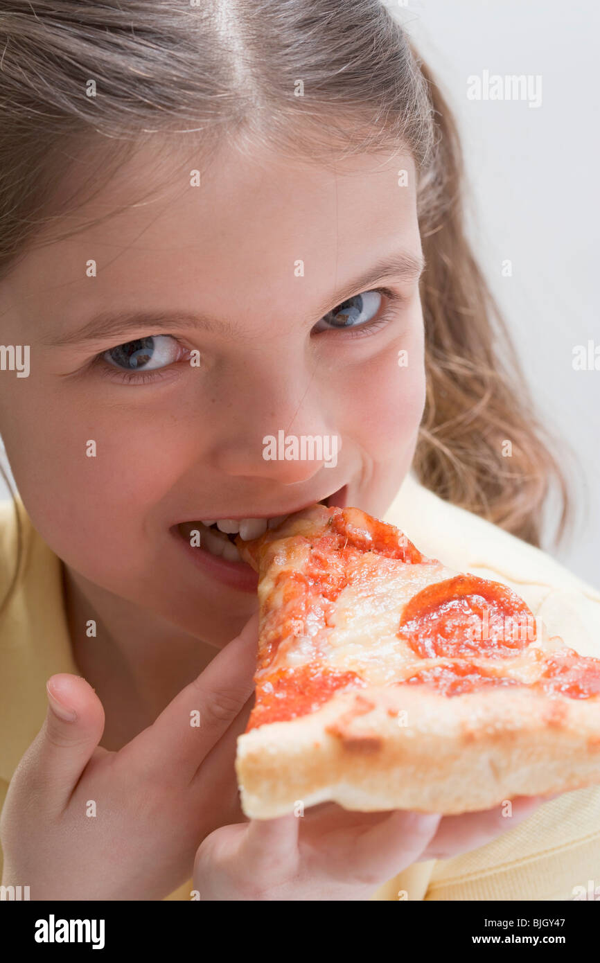 Girl biting into a slice of salami pizza Stock Photo - Alamy
