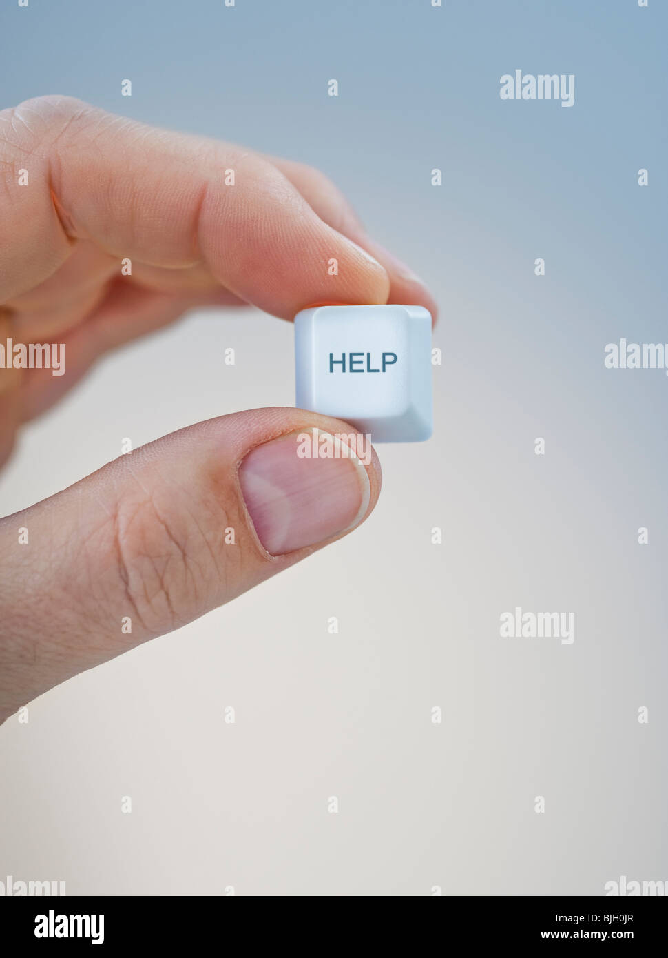 Hand holding keyboard help key Stock Photo - Alamy