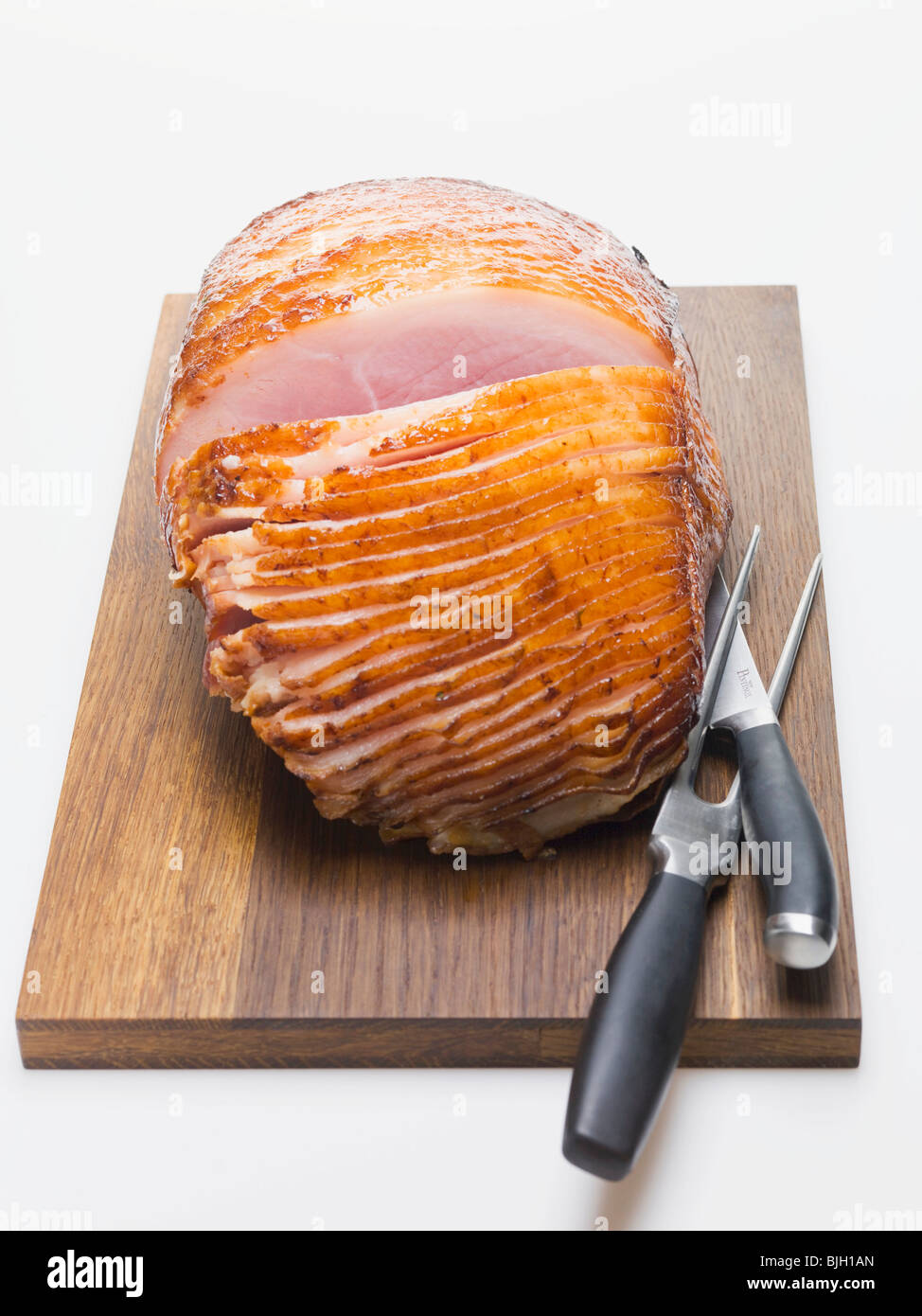 Glazed ham on chopping board with carving cutlery Stock Photo - Alamy