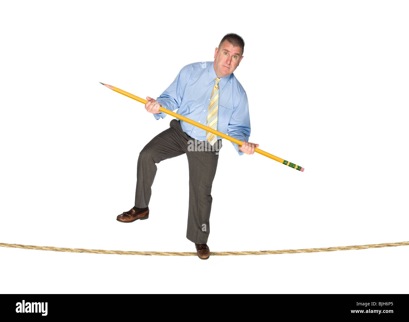 A businessman balancing on a tightrope using a giant pencil as a ...