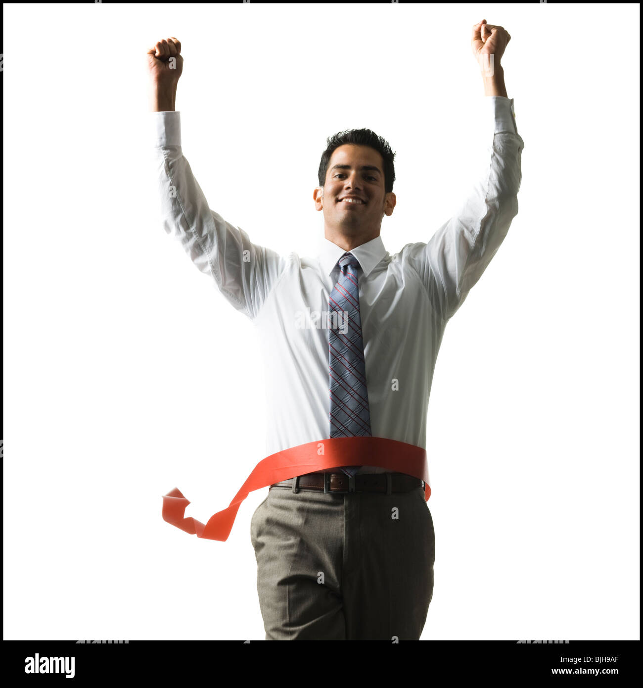 businessman crossing a finish line of a red ribbon with arms raised in ...
