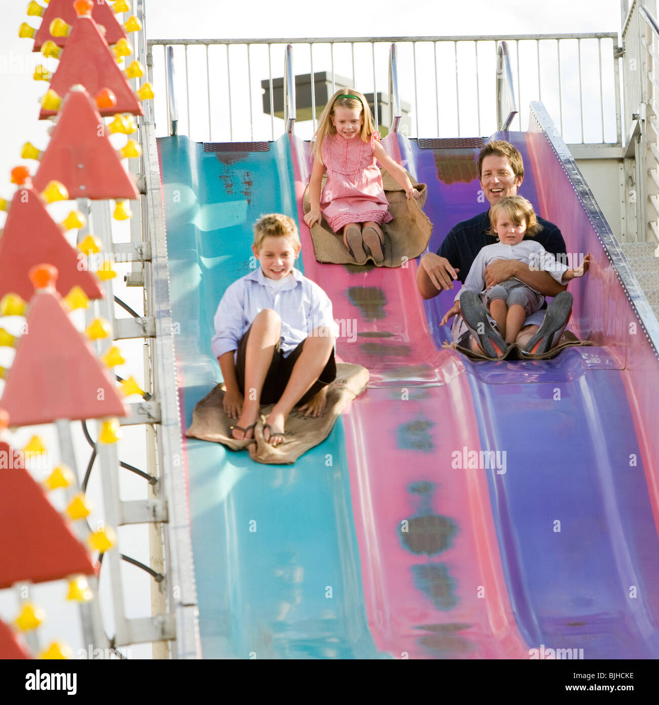family at the carnival riding on the fun slide together Stock Photo - Alamy