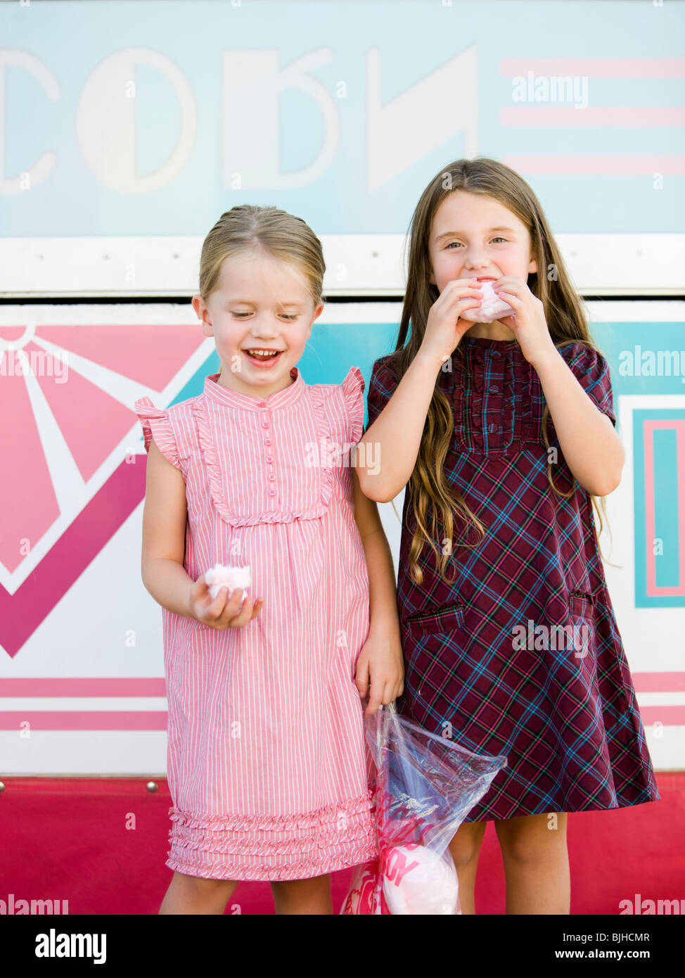 two sisters eating cotton candy at the carnival Stock Photo - Alamy