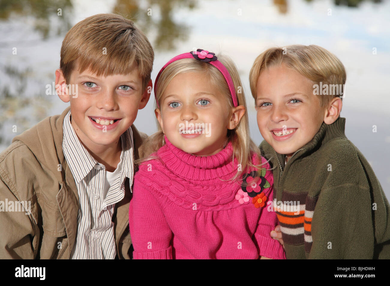 three cute siblings together outside with water background Stock Photo ...