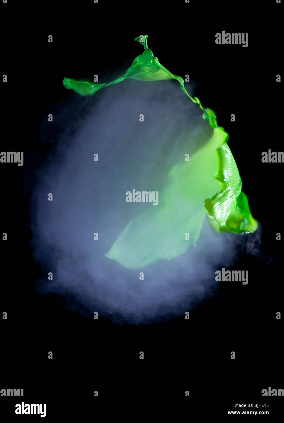 A smoke filled green balloon bursting when shot with an air rifle ...