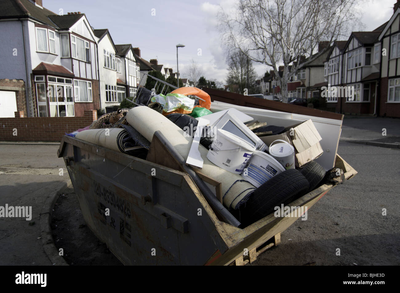 Fully loaded skip in the road readtyto be taken away Stock Photo - Alamy