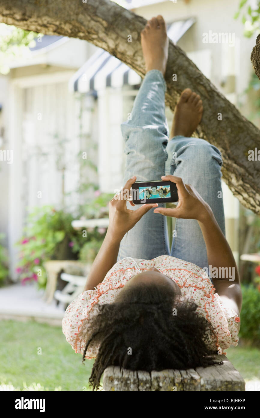 woman lying under a tree watching a portable media device Stock Photo ...