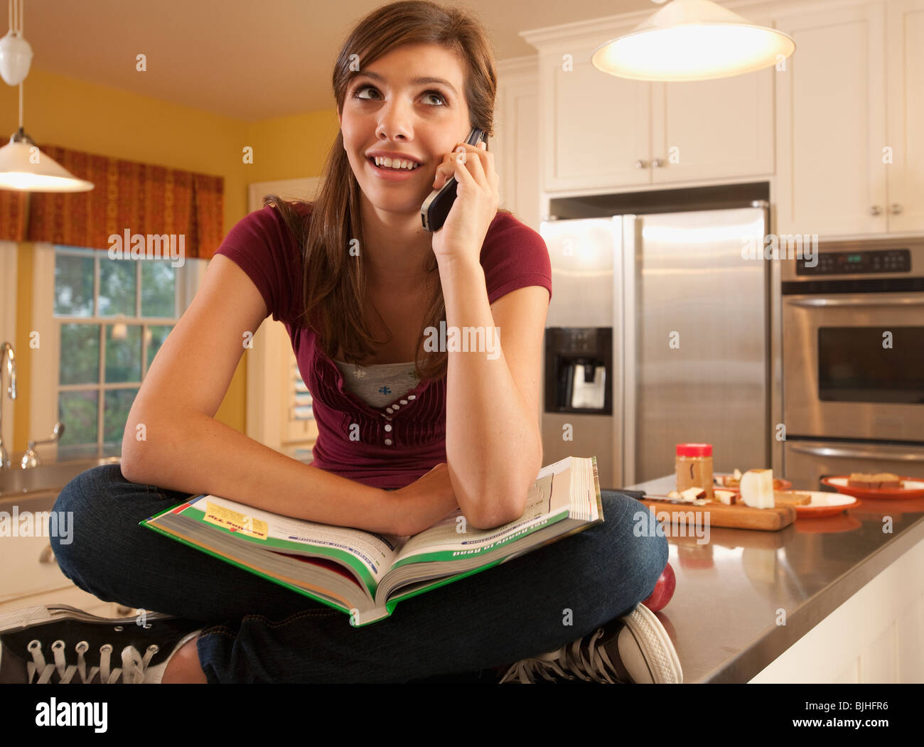Girl sitting on kitchen counter Stock Photo - Alamy