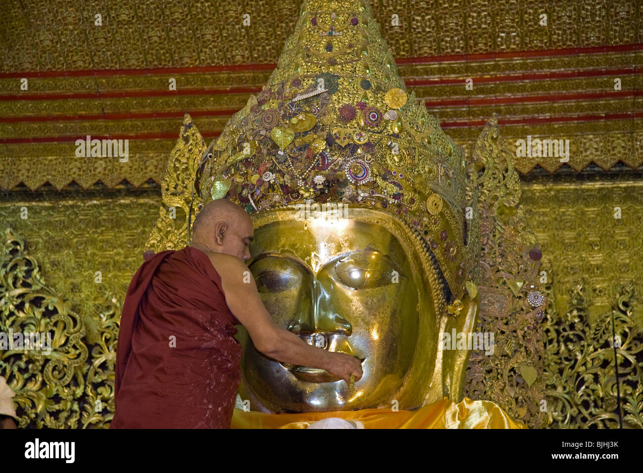 Buddhist monk performing the daily ritual cleaning of the Mahamuni ...