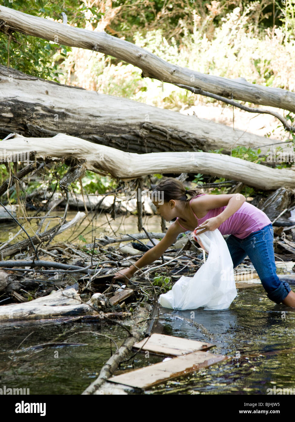 girl picking up trash in a river Stock Photo - Alamy