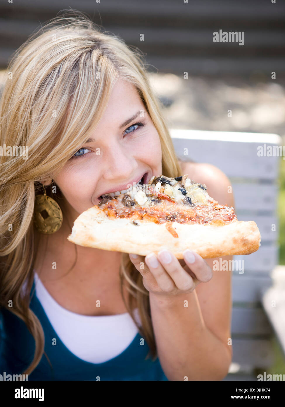 woman eating pizza while looking at camera and smiling Stock Photo - Alamy