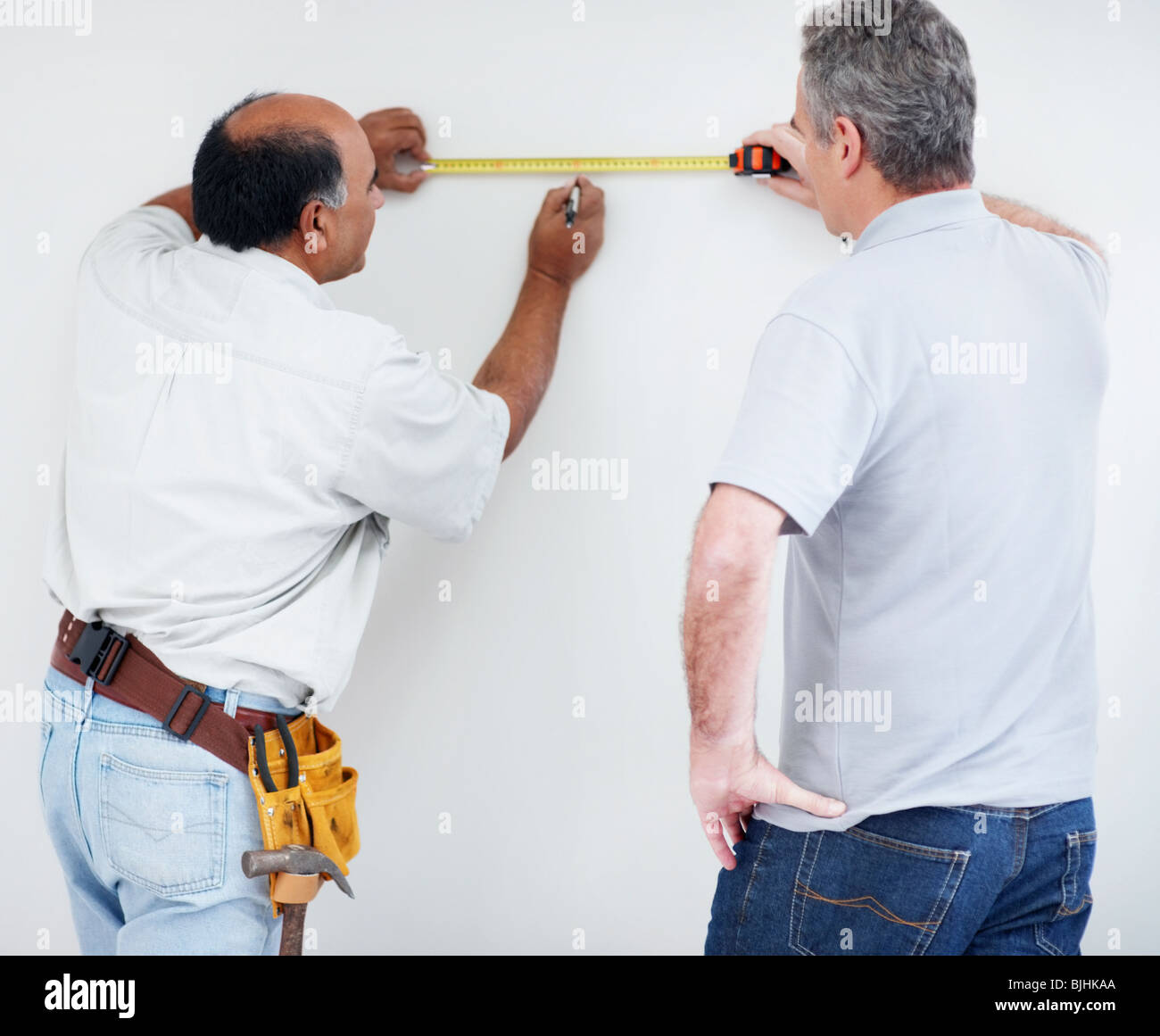 Men measuring wall Stock Photo - Alamy