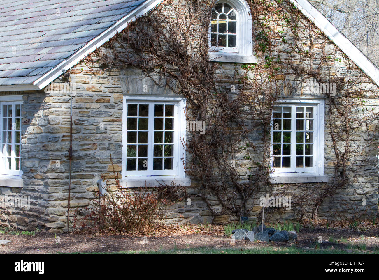 The gable end of a country cottage with ceder shakes stone chimney and ...