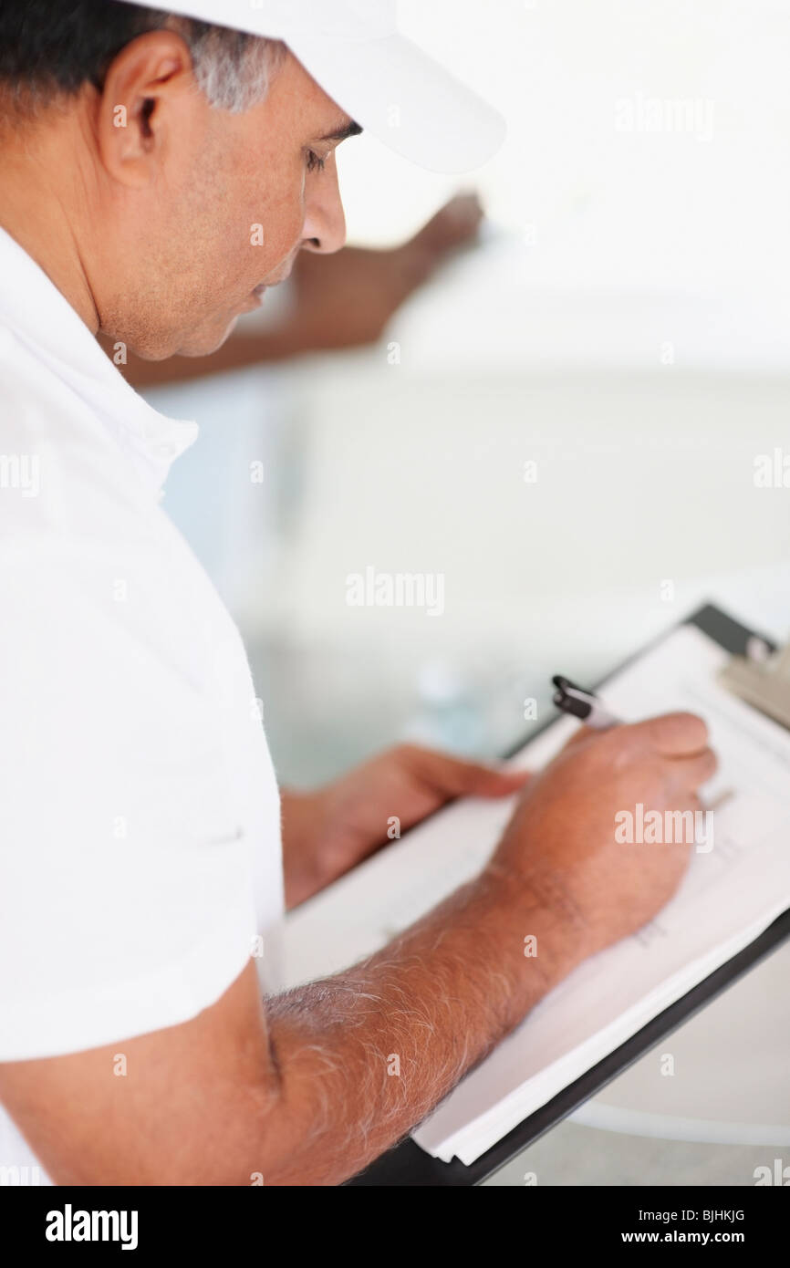 Repair person writing on clipboard Stock Photo - Alamy