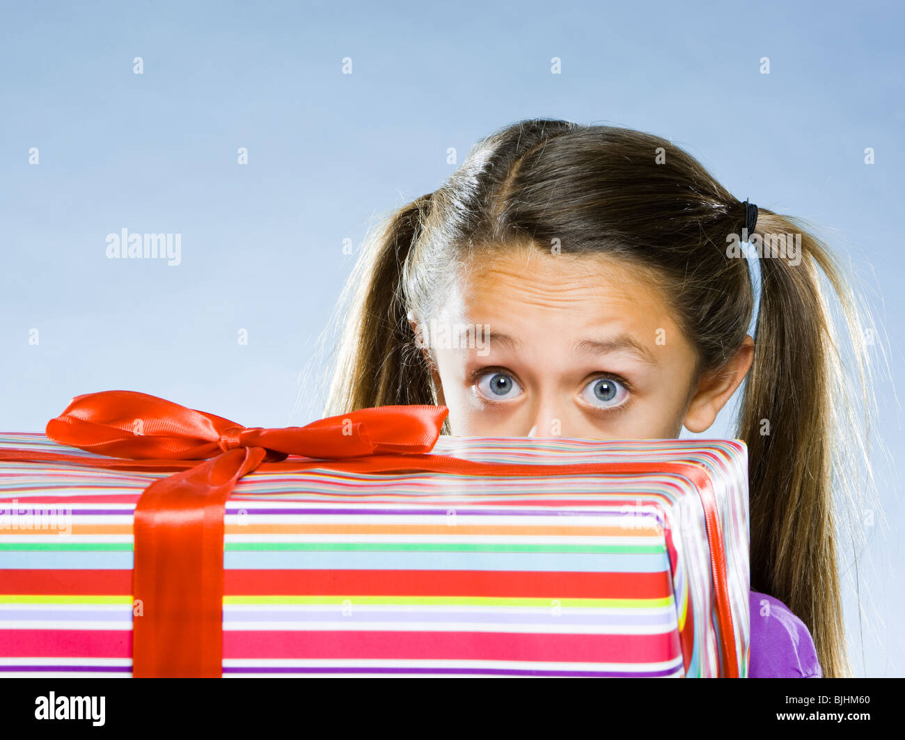 girl looking at the camera from behind a present Stock Photo - Alamy