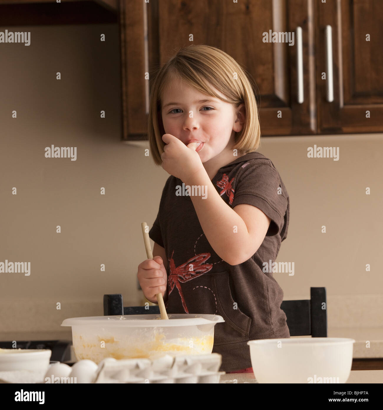 Young girl tasting cookie batter Stock Photo - Alamy