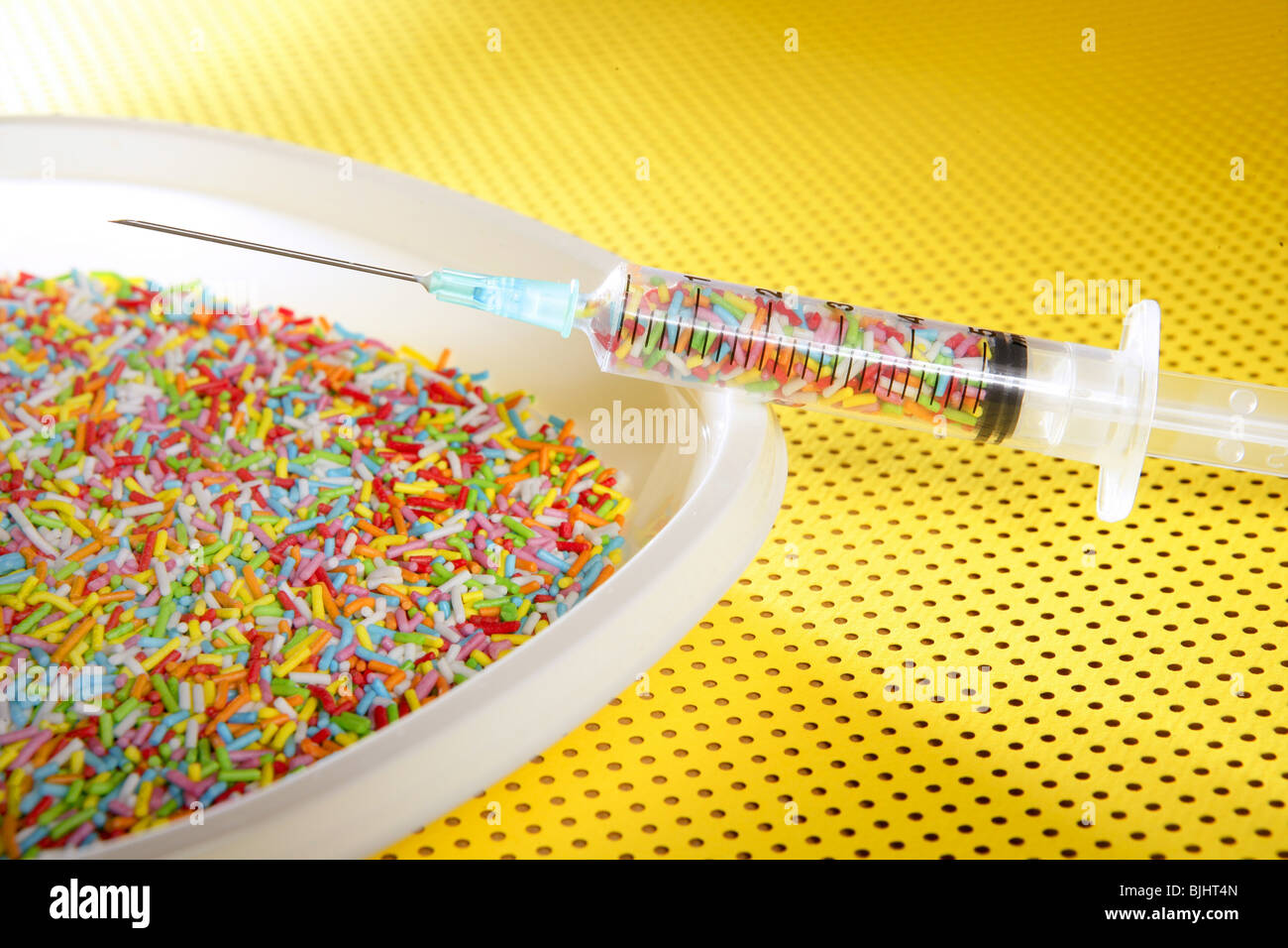 Little colorful candy syringe over yellow background, health metaphor ...