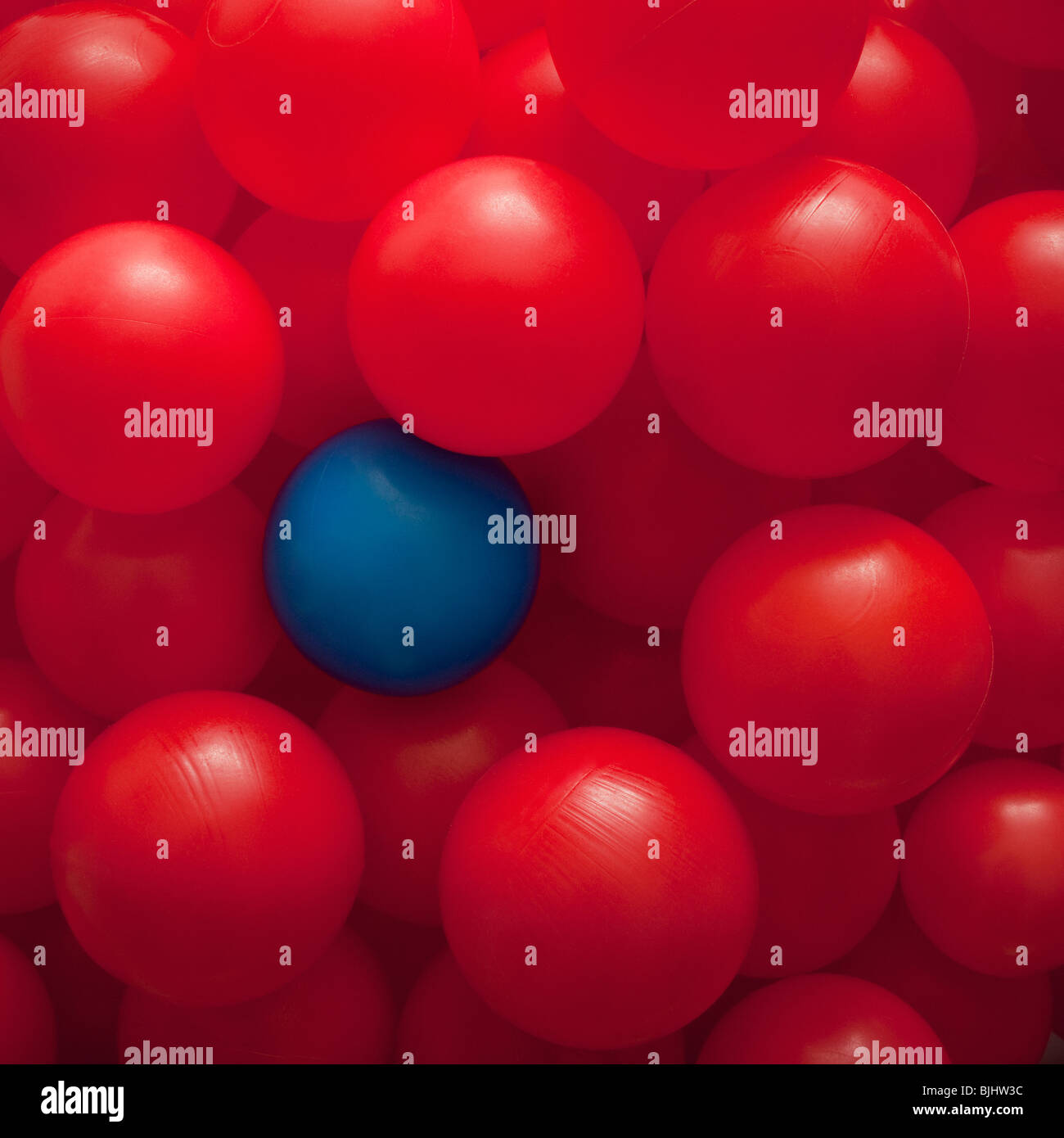 One blue ball amongst many red balls Stock Photo - Alamy