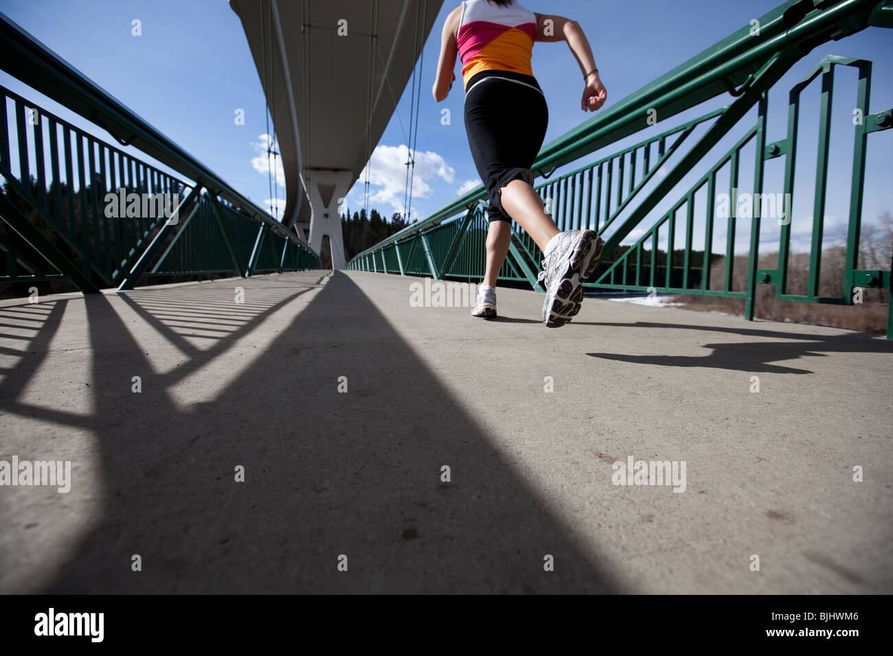 Young Woman Running away from camera on pedestrian bridge in city Stock ...