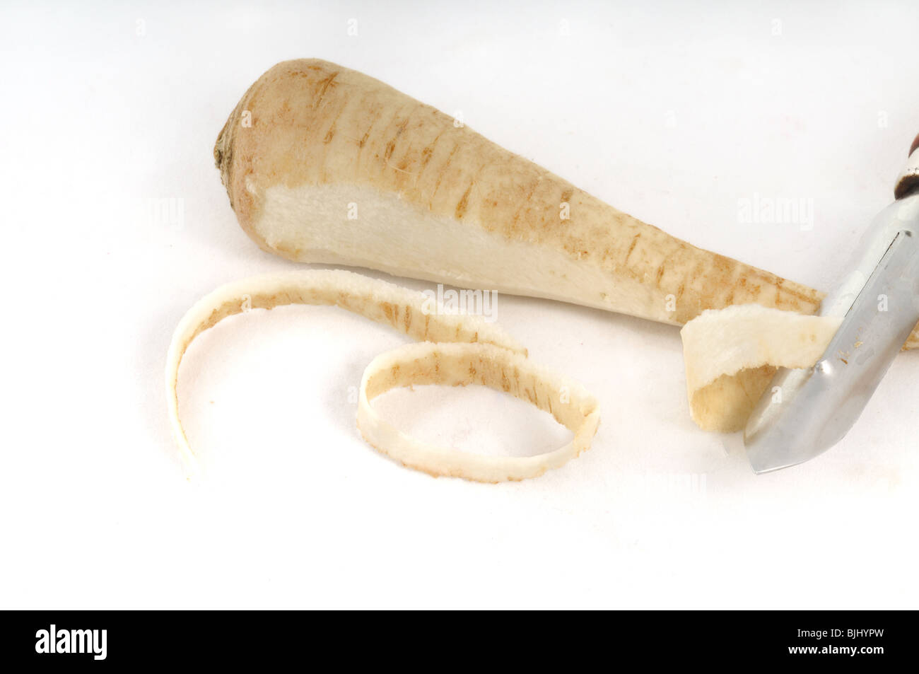 Parsley root during peeling on a white background Stock Photo - Alamy