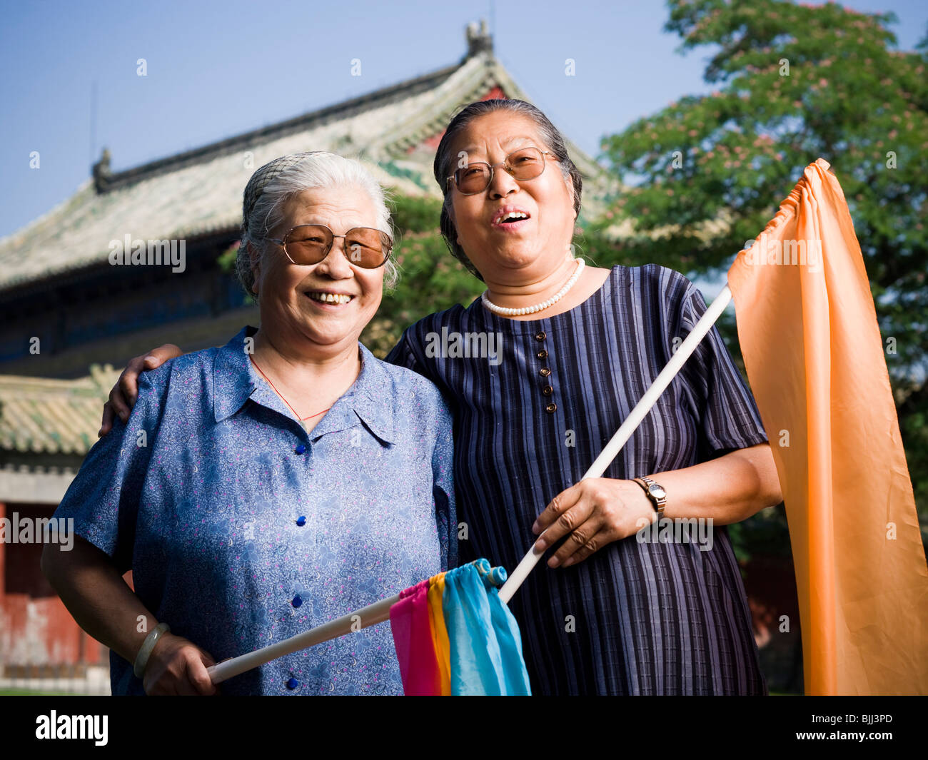 Two women embracing outdoors with flags and pagoda in background Stock ...