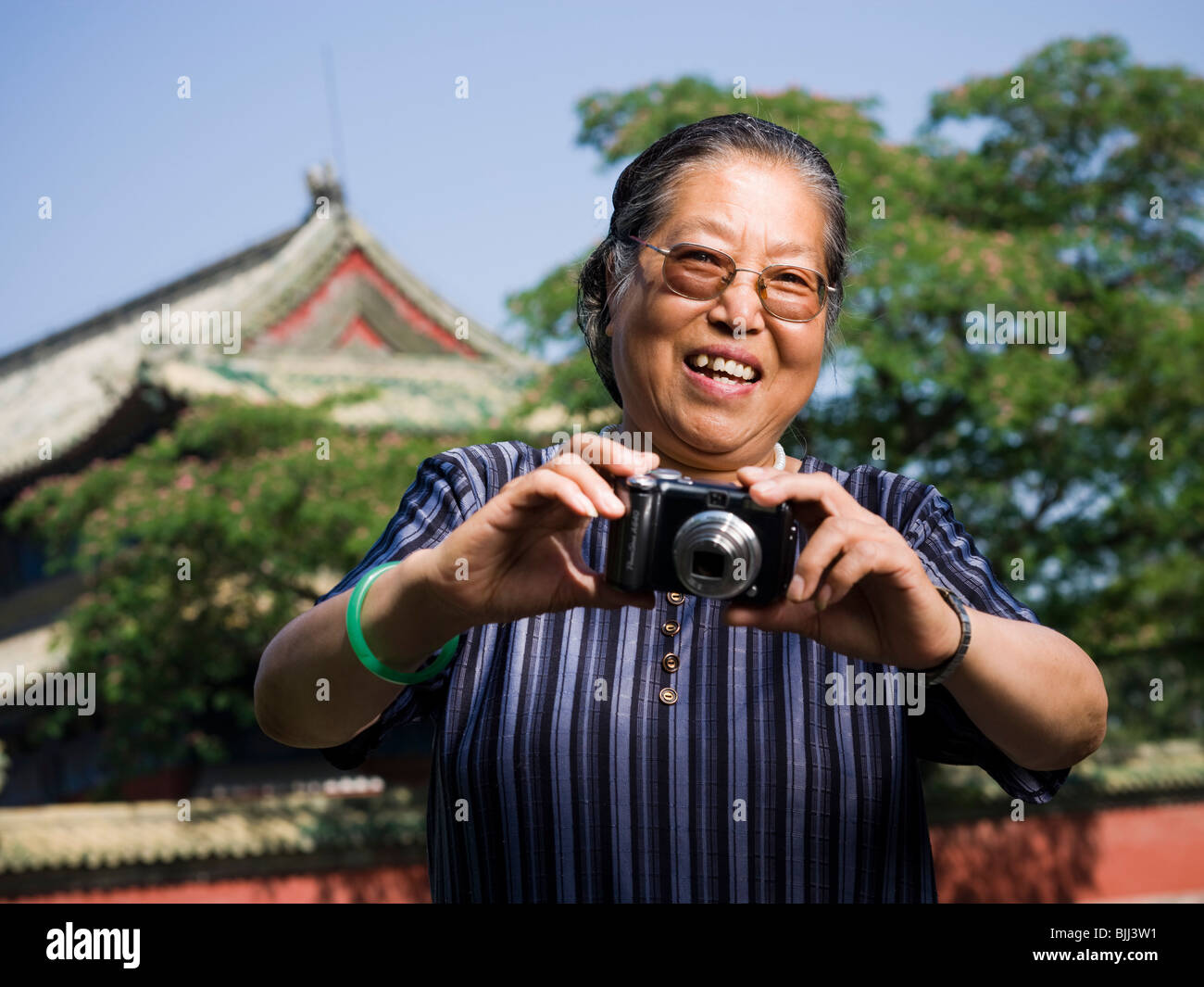 Mature woman with camera outdoors smiling Stock Photo - Alamy