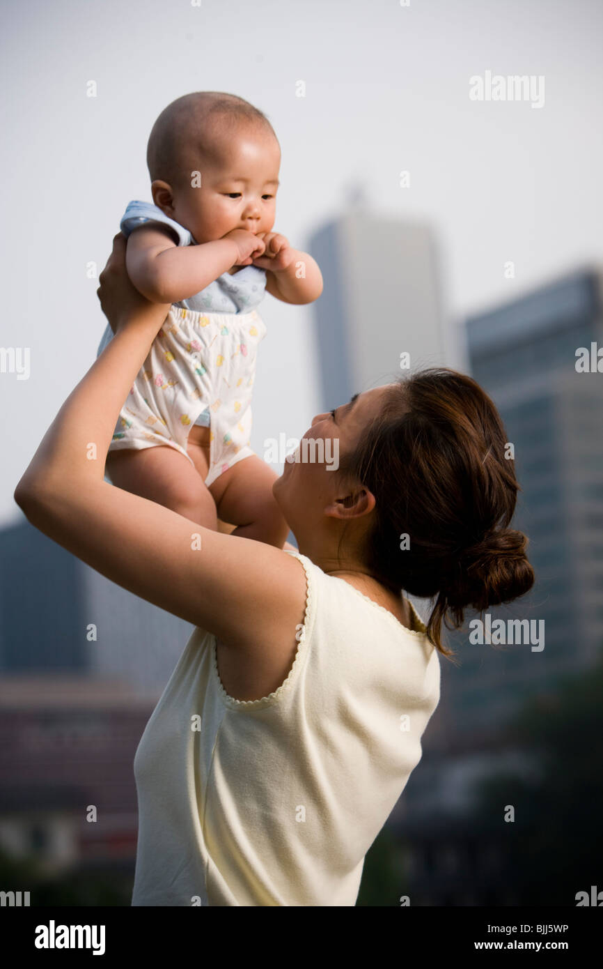 Woman lifting baby outdoors and smiling Stock Photo - Alamy