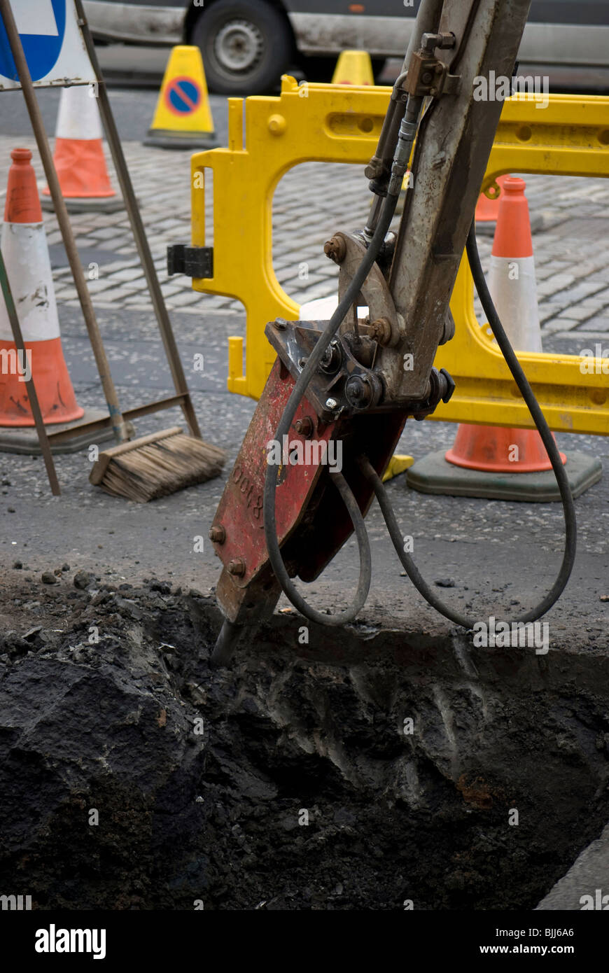 Hydraulic drill attachment on a digger digging a hole in the road Stock ...