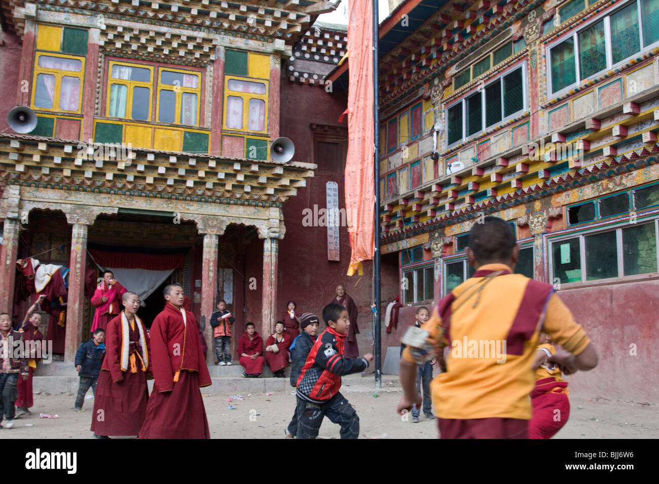 Young novice monks playing with a ball in the courtyard of a monastery ...