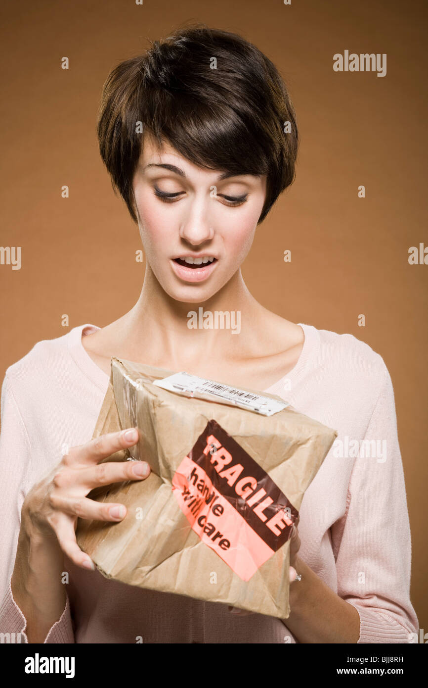 Woman holding crushed cardboard box with fragile label Stock Photo - Alamy