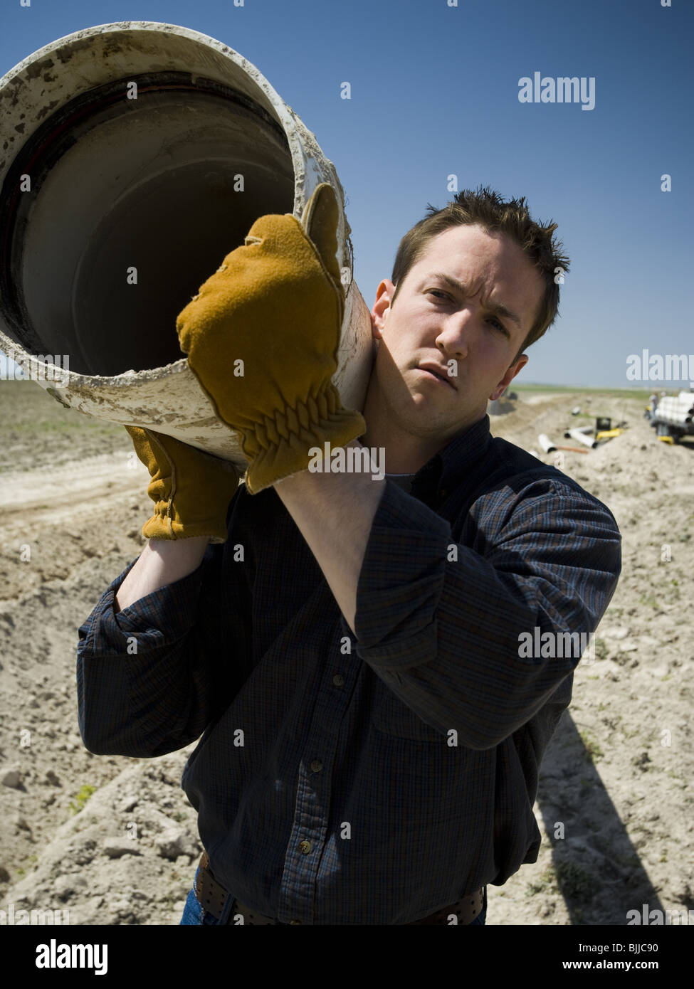 Man carrying pipe outdoors smiling Stock Photo - Alamy