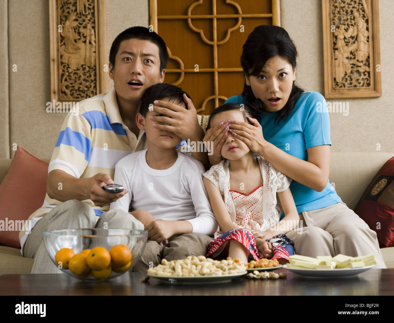 Family watching television with parents covering children's eyes Stock ...