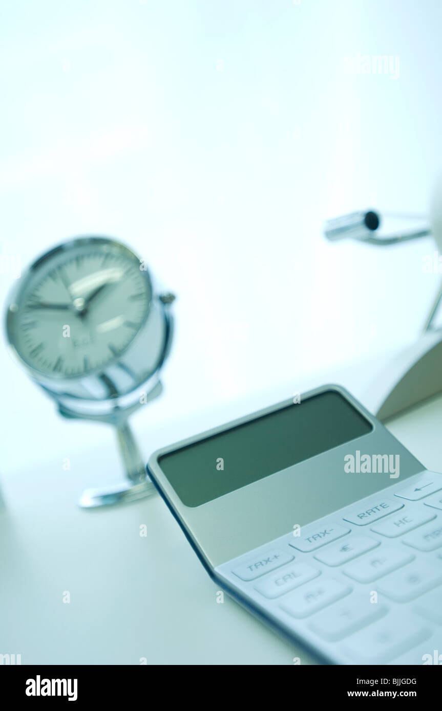 Calculator and clock on desk Stock Photo - Alamy