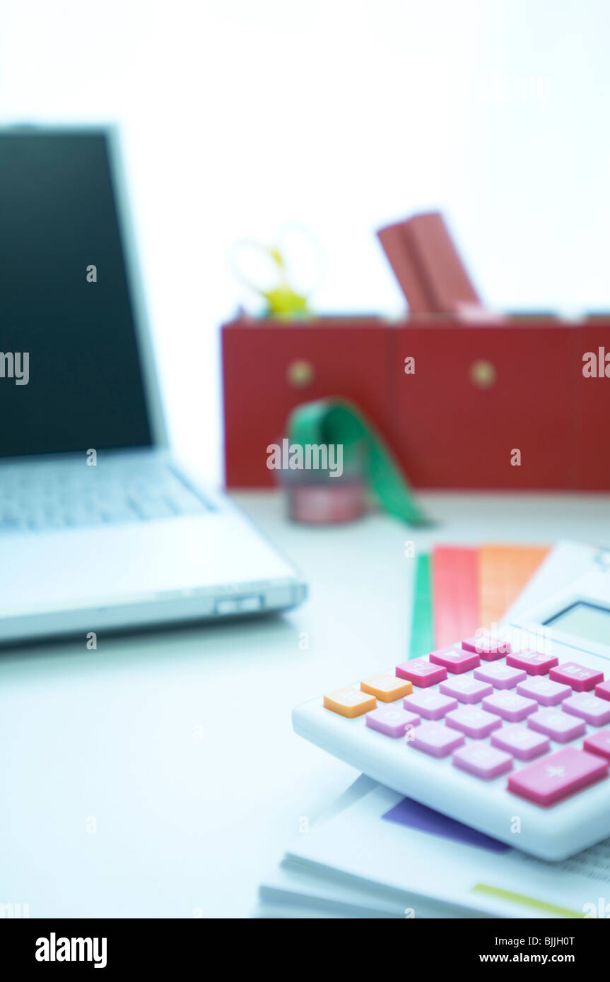 Laptop on desk with files and calculator Stock Photo - Alamy