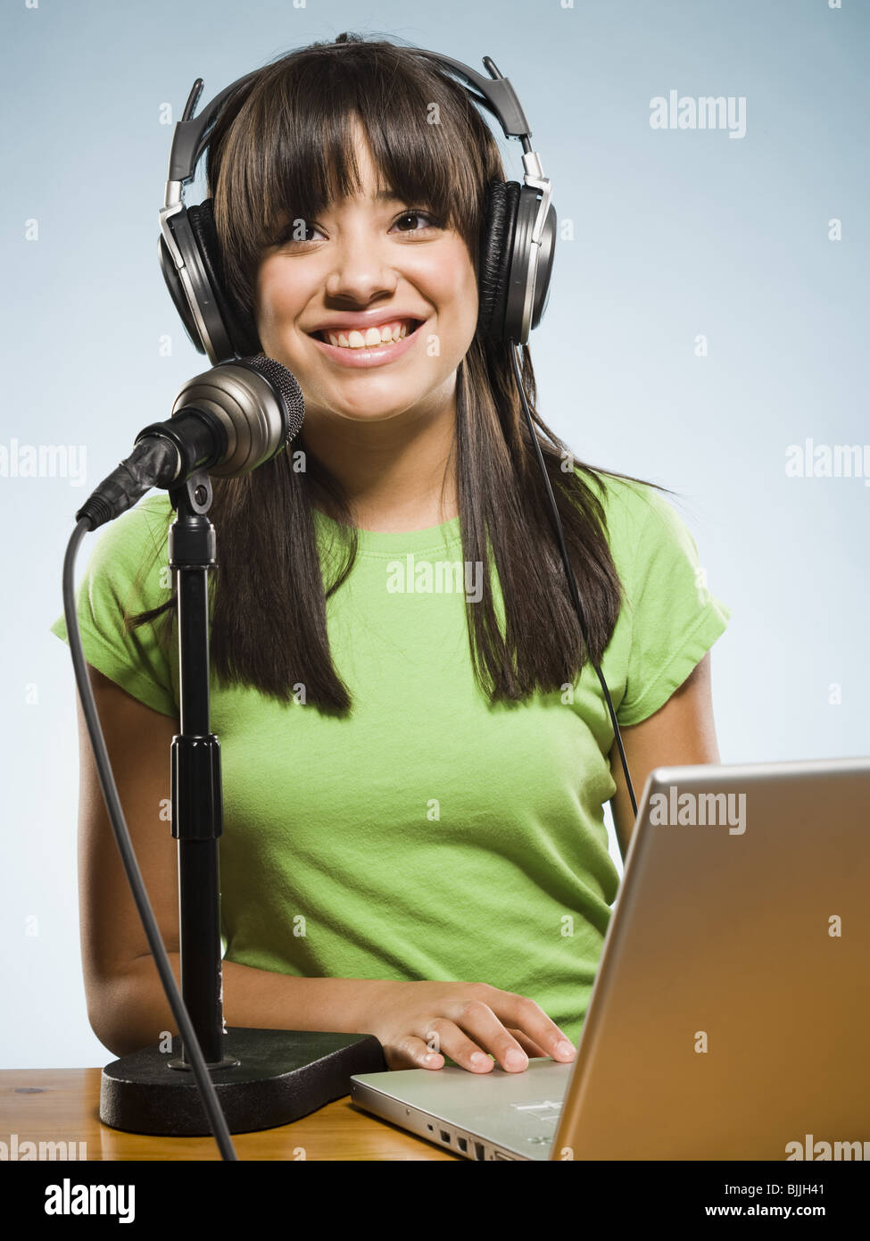 Woman with headphones and laptop singing into microphone Stock Photo ...