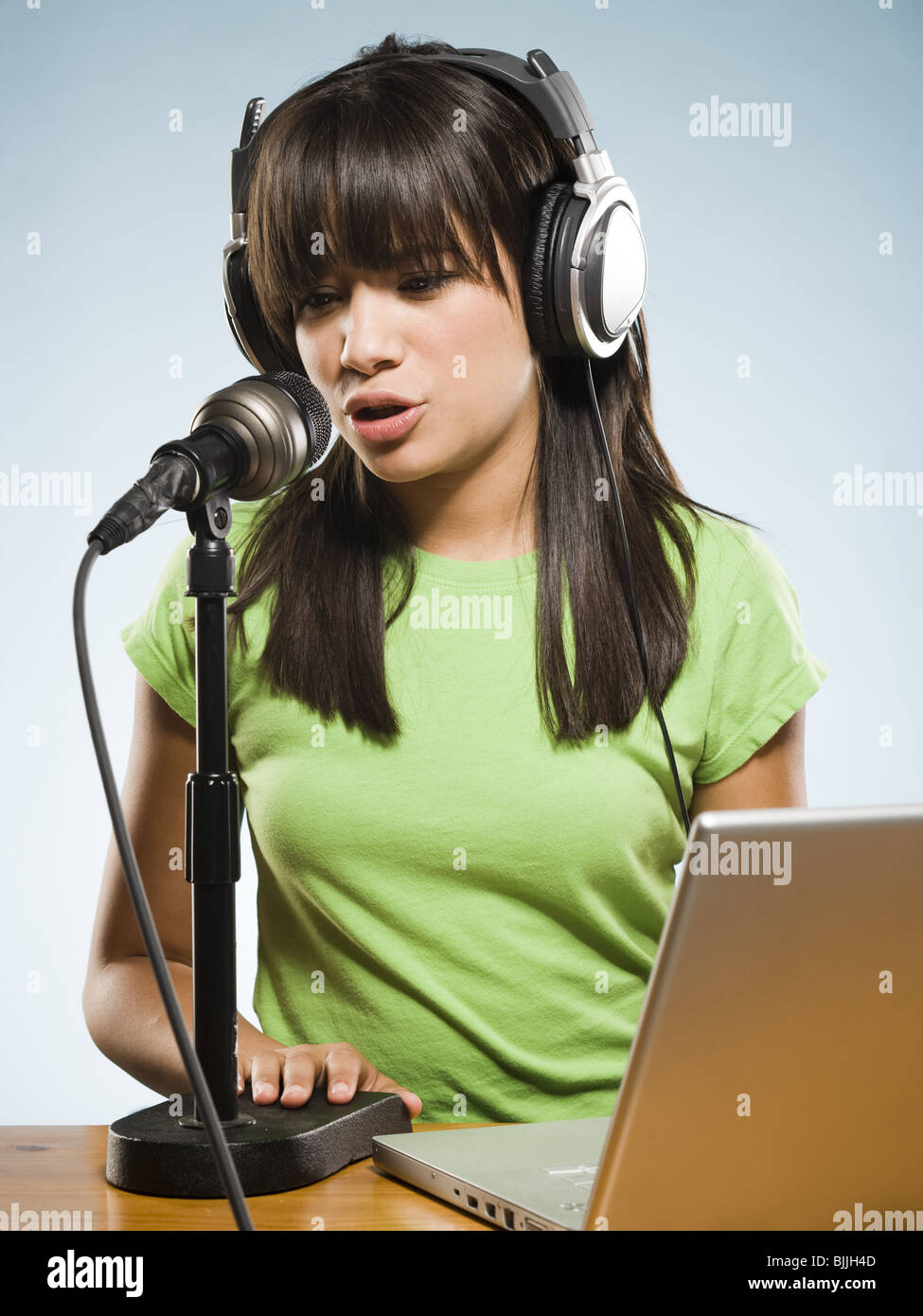 Woman with headphones and laptop singing into microphone Stock Photo ...